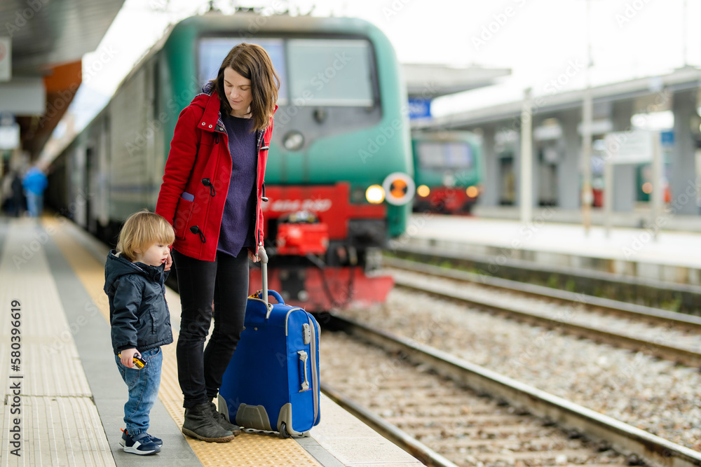 Young mother and her toddler son on a railway station. Mom and little ...