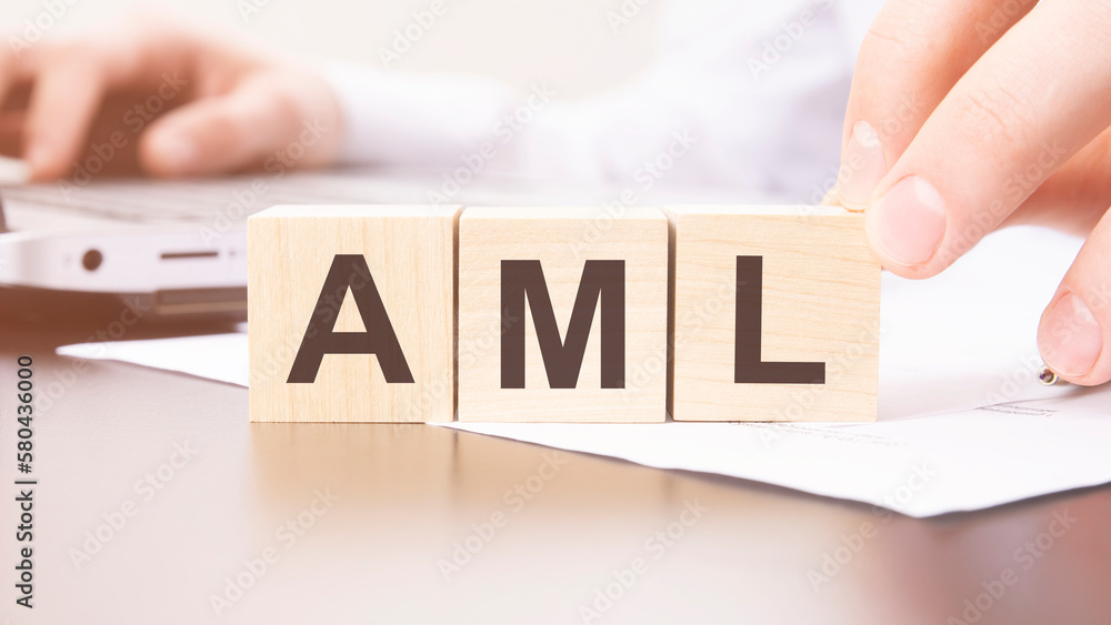 hand holding wooden cube with AML text on table background. financial ...