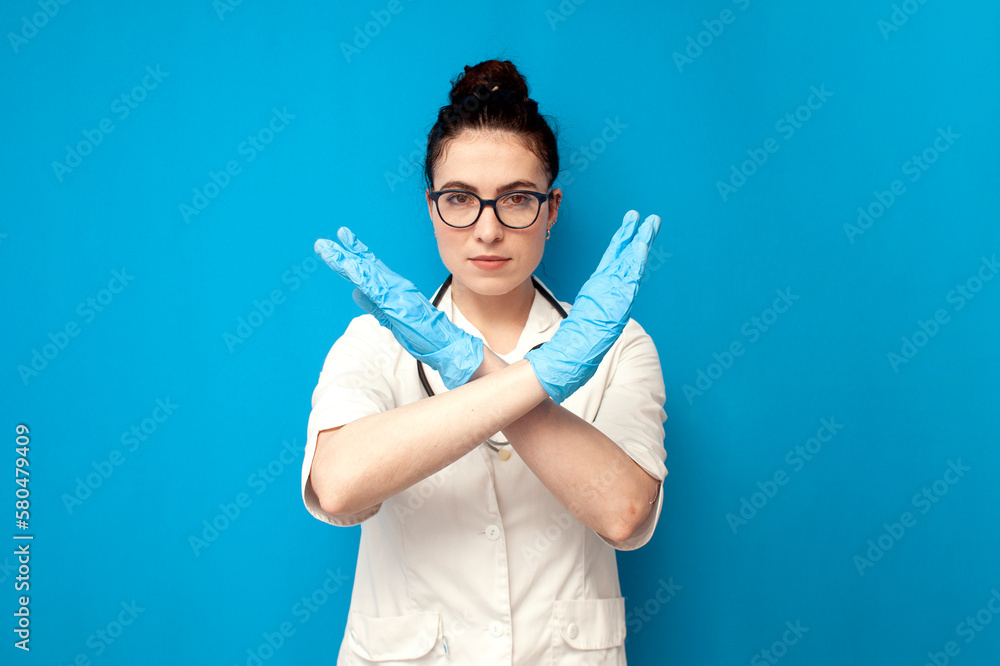doctor woman in uniform shows stop gesture with hand on blue background ...