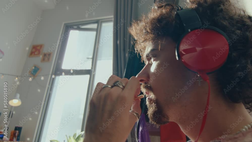 Close-up view of young man in headphones listening to music, smoking a ...