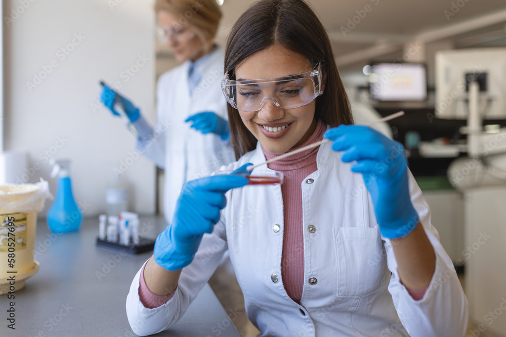 Petri dish in hand of young scientist near microscope in laboratory ...