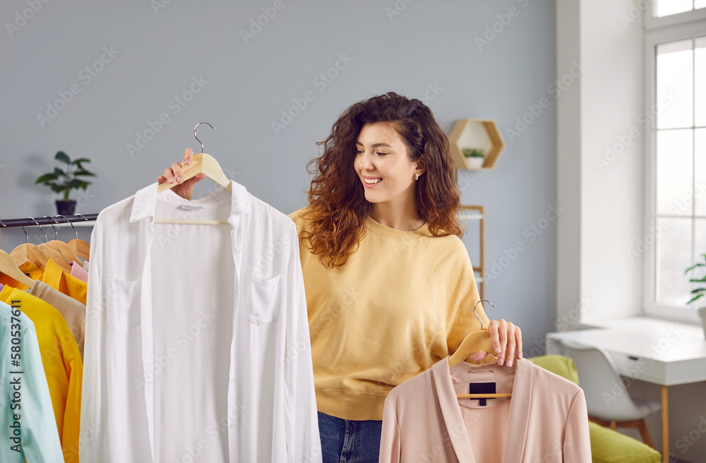 Beautiful woman choosing clothes on rack at home. Attractive smiling ...