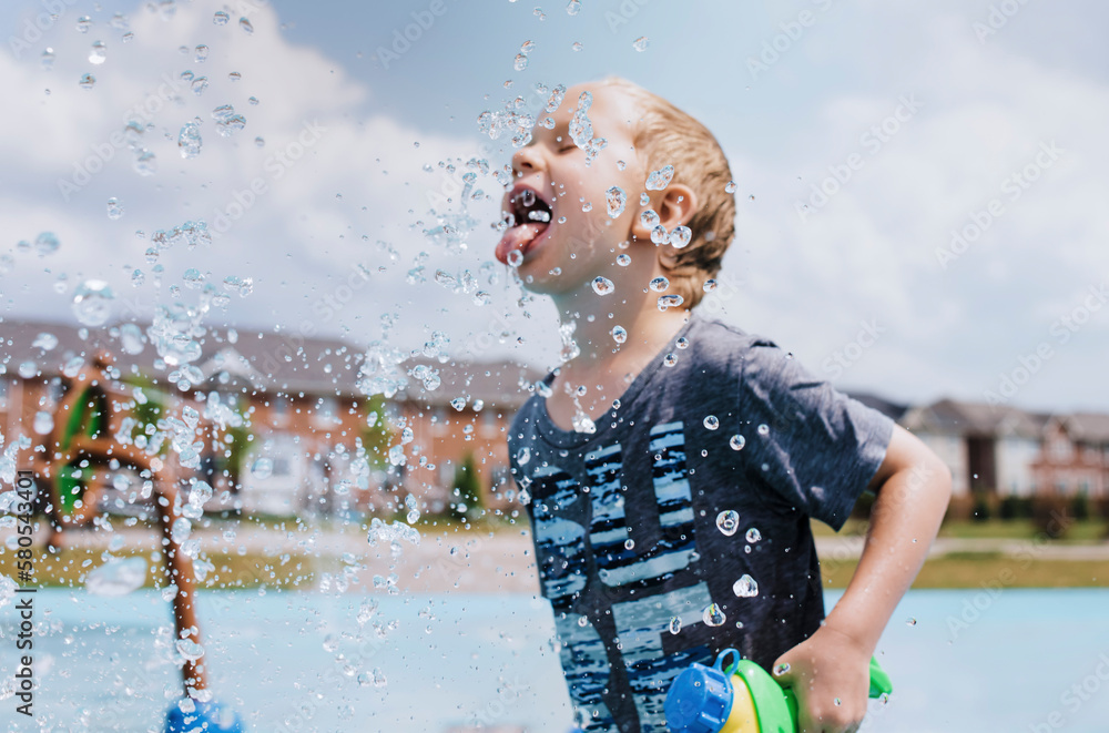 Playful boy sticking out tongue while standing spraying water Stock ...