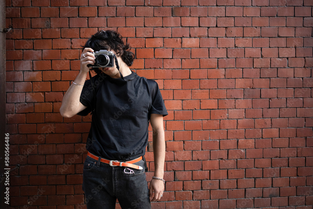Man photographing through camera in front of brick wall Stock Photo ...