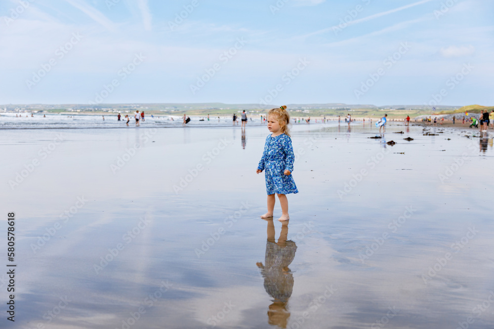 Little cute toddler girl at the Ballybunion surfer beach, having fun on ...