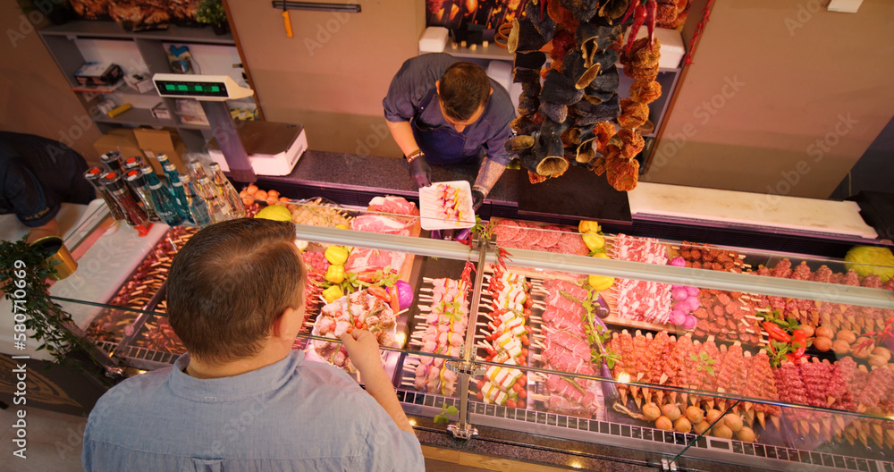 Top view butcher serving costumer by placing chicken barbeque on ...
