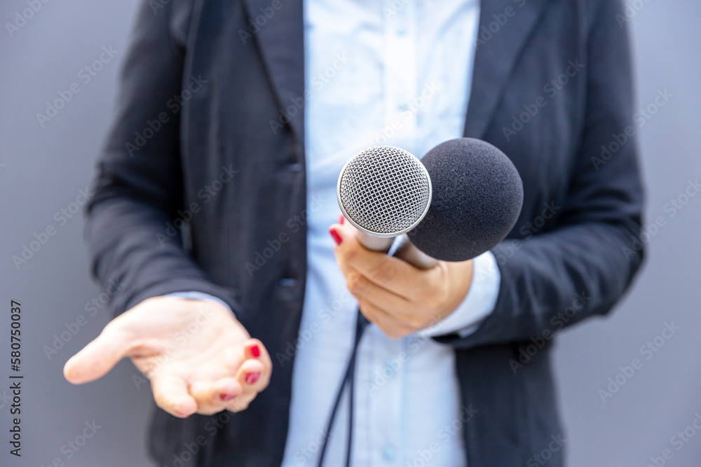 Female reporter holding microphone and gesturing during media interview ...