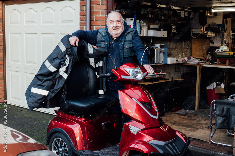 Portrait of elderly man standing near mobility scooter on the ...