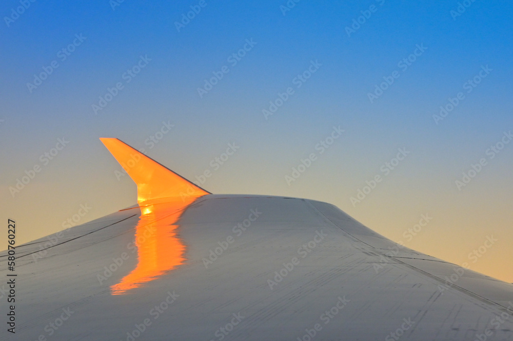 Wing and curved wing tip of a modern passenger jet in flight at sunset ...