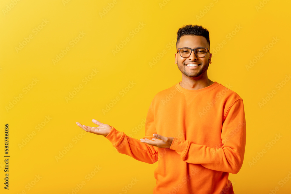 Cheerful indian man pointing at copy space with his palms, empty place ...