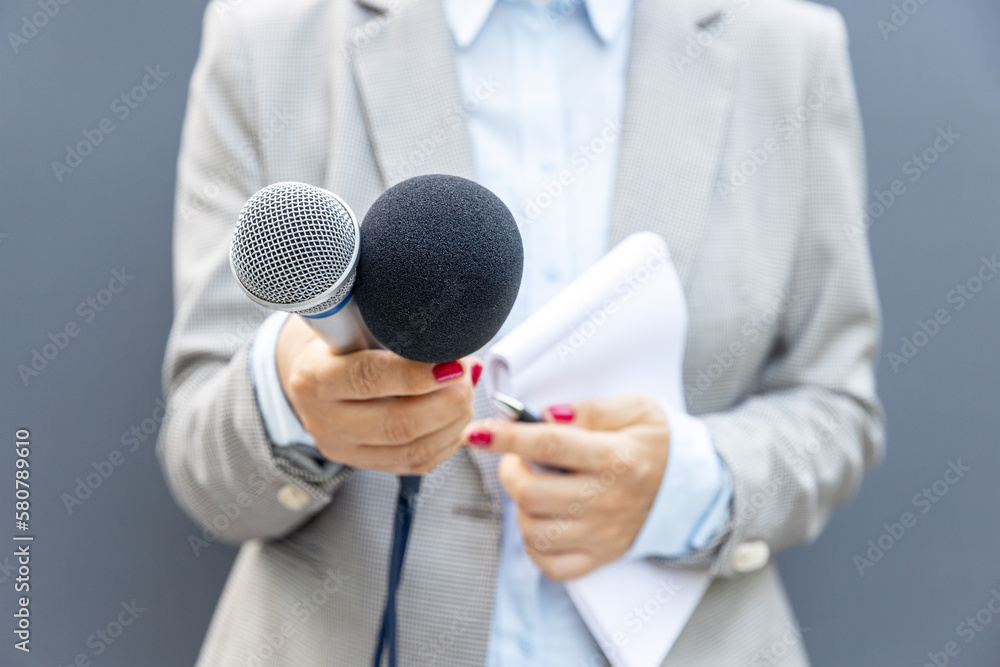 Female journalist holding microphone during media interview. Freedom of ...