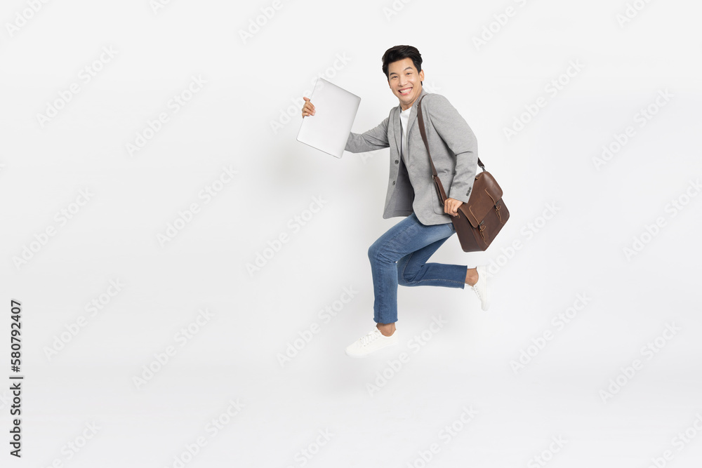 Young businessman jumping in air with laptop computer and brown leather ...
