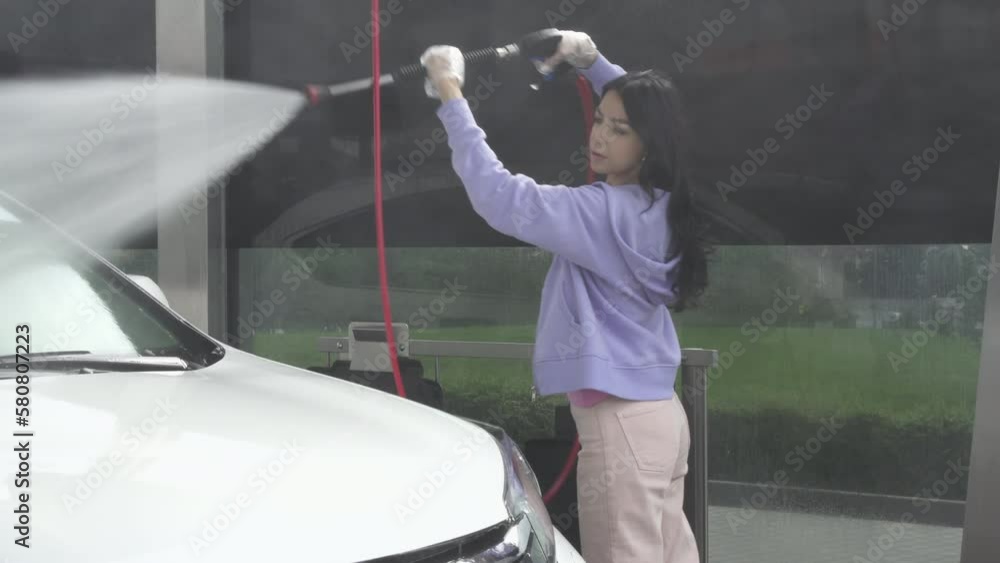 Washing car on a touchless car wash. Cheerful young woman cleans a car ...