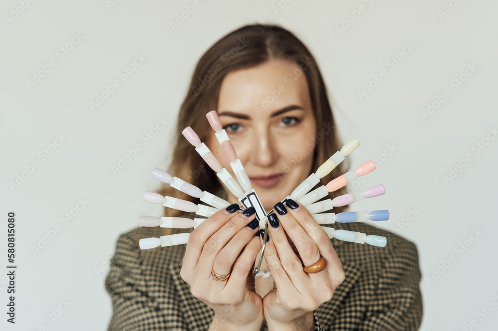 Professional woman master of manicure posing with samples of nails. The ...