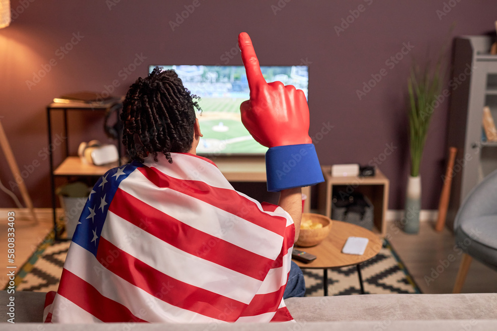 Back view at sports fan wearing flag while watching baseball match on ...