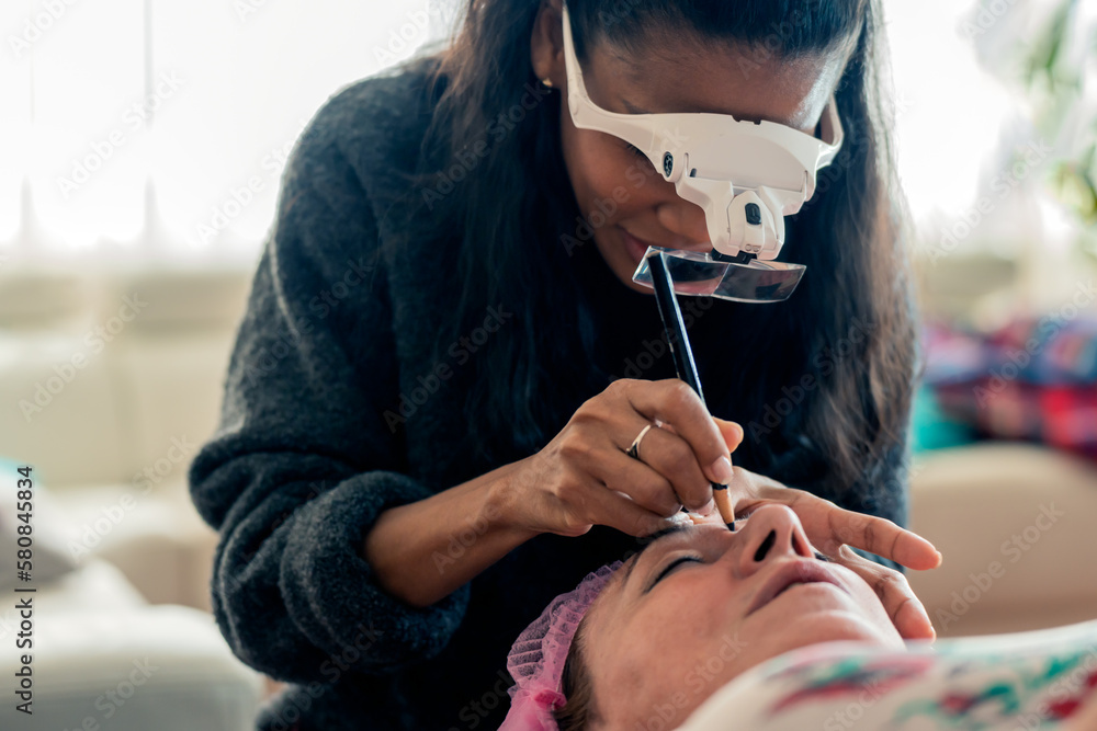 Crop female black microblading master in magnification goggles drawing ...