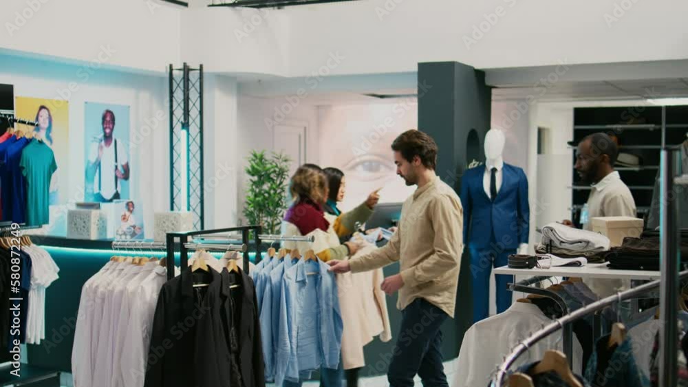 Retail worker helping customer to buy shirts at mall, diverse people ...