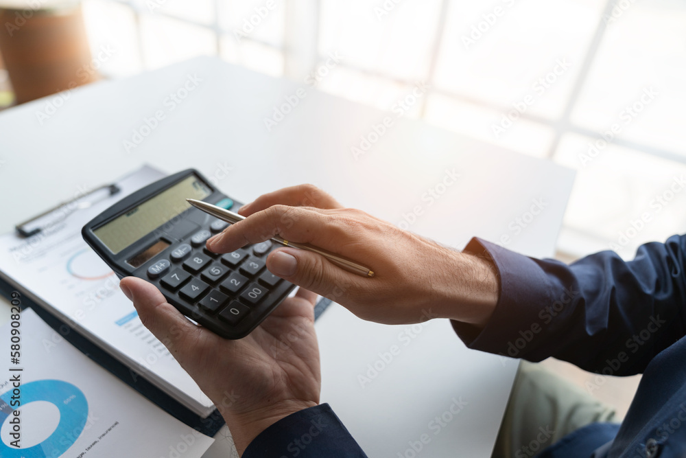 Investing young businessman accountant using calculator for income ...