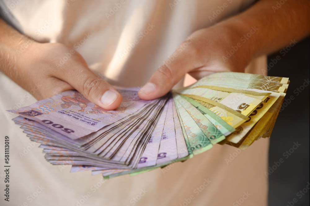Hand of man holding Sri Lanka banknotes of different denominations ...