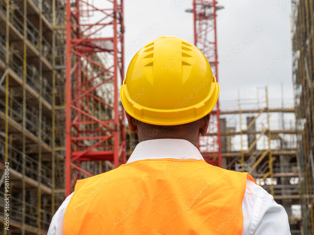 Rear view of a back turned construction worker wearing ppe looking at ...