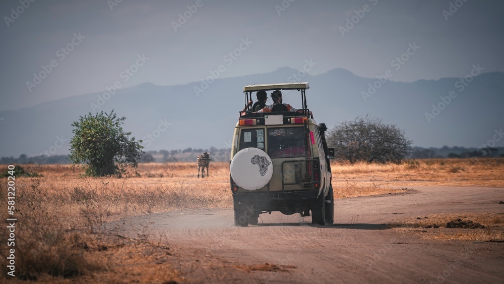 Off-road safari vehicle driving among wild animals in the Serengeti ...