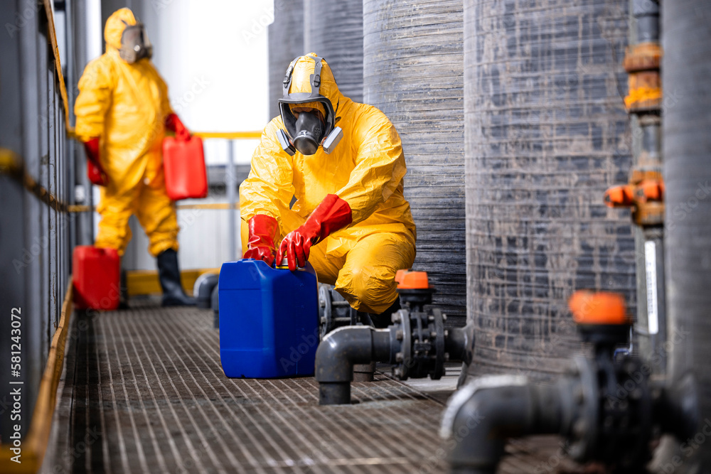 Experienced and protected workers in yellow chemicals suit, gas masks ...
