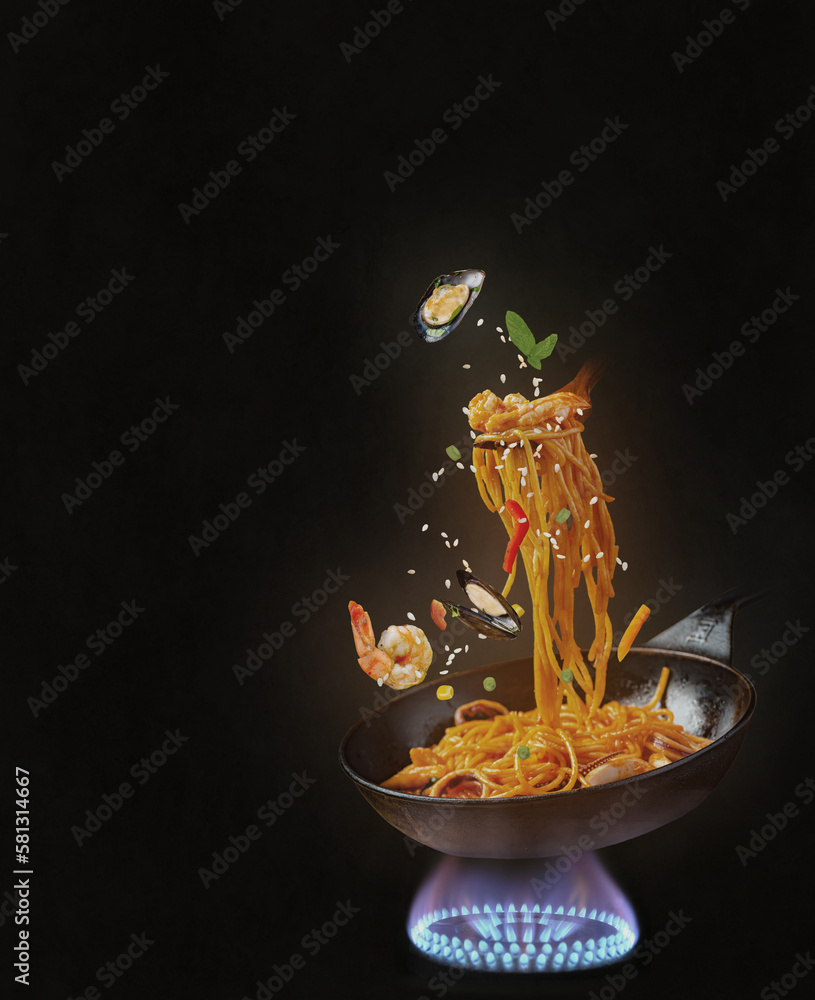 Flying Spaghetti with sea food and vegetables in a pan on fire - black ...