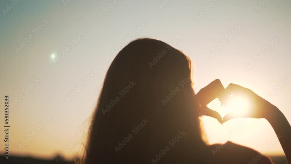 Girl folded her hand heart at sunset.Silhouette of girl in nature ...