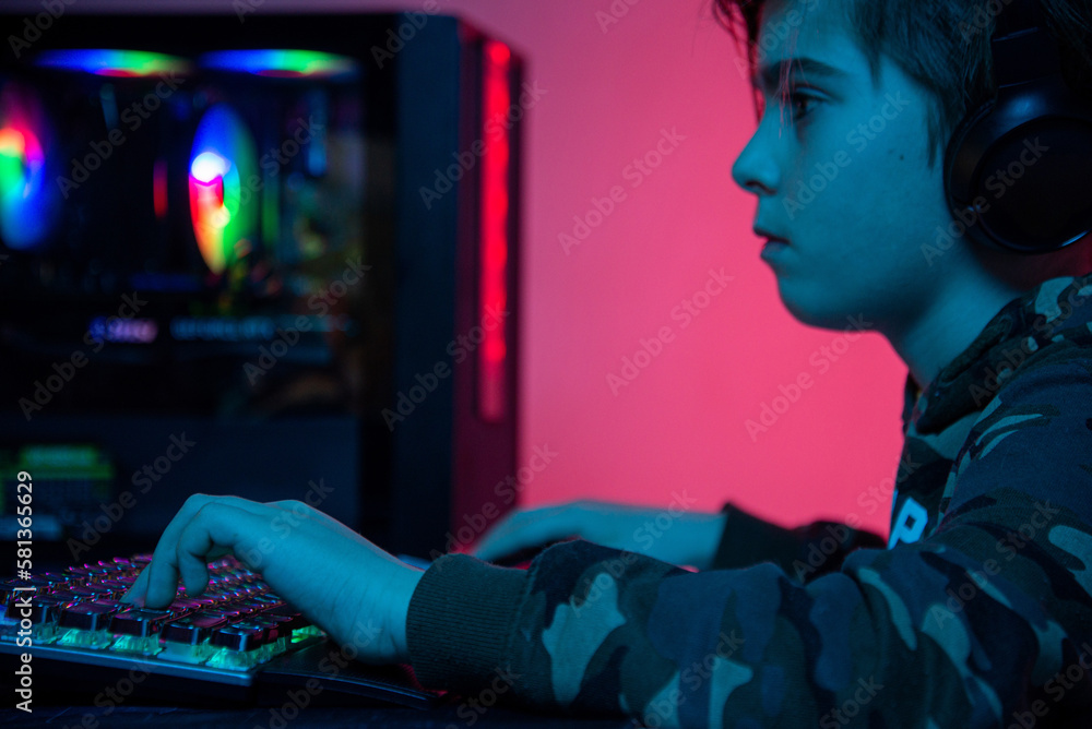 Foto de immersed teenage gamer boy playing video games on computer in ...