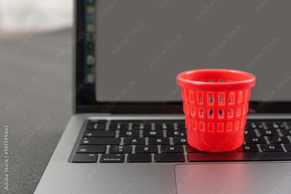 Miniature toy trash can on laptop keyboard. Concept of deleting files ...