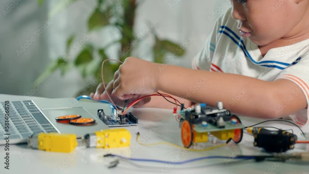 Asian kid boy plugging energy and signal cable to sensor chip with Arduino robot car, Little ...