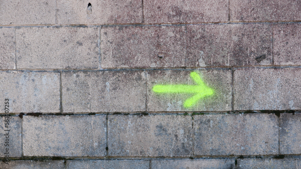 Flecha pintada con spray amarillo fluor en pared de bloques de hormigón ...