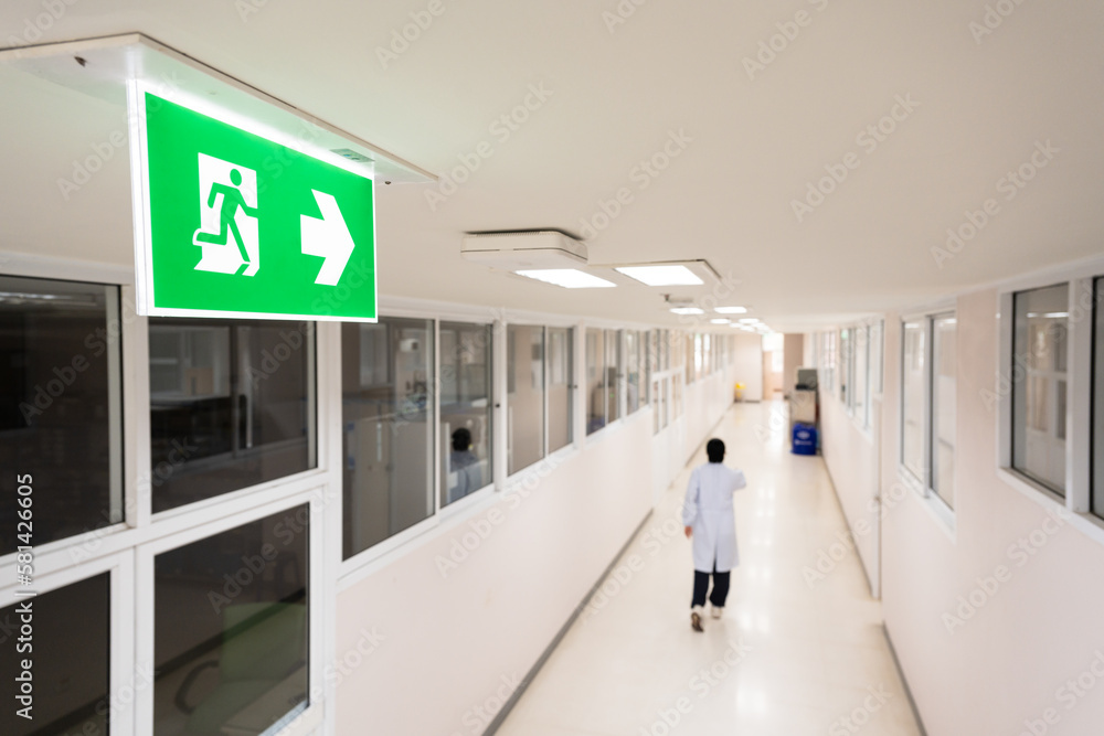 Selective fire exit sign on white ceiling.Green fire escape sign hang ...