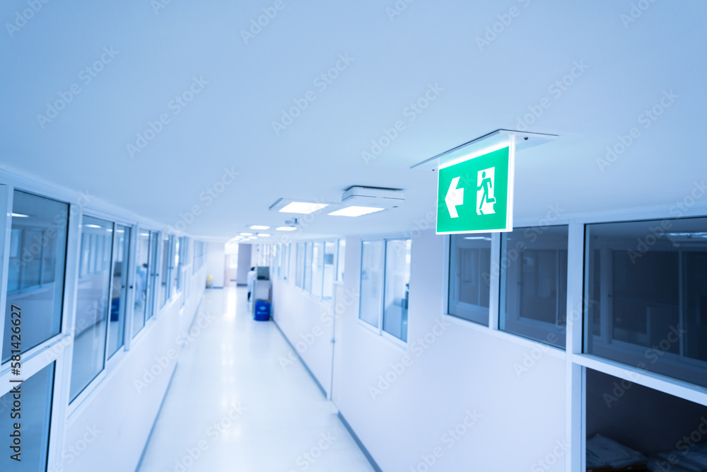 Selective fire exit sign on white ceiling.Green fire escape sign hang ...
