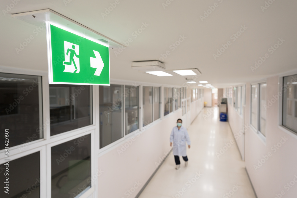 Selective fire exit sign on white ceiling.Green fire escape sign hang ...