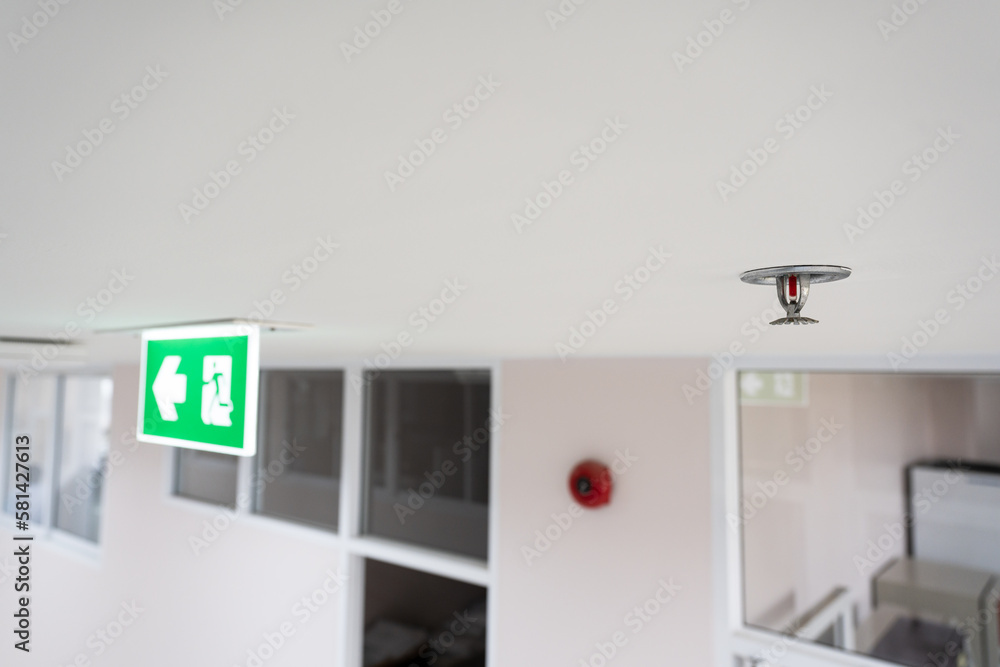 Selective fire exit sign on white ceiling.Green fire escape sign hang ...