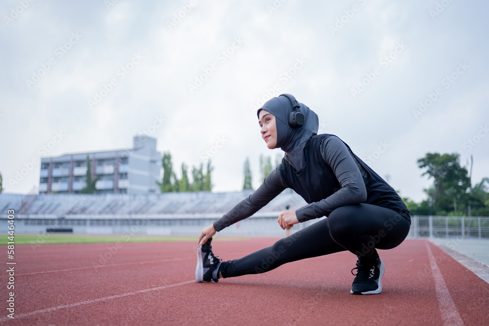 Foto de A young asian Muslim woman wearing a black hijab is exercising ...
