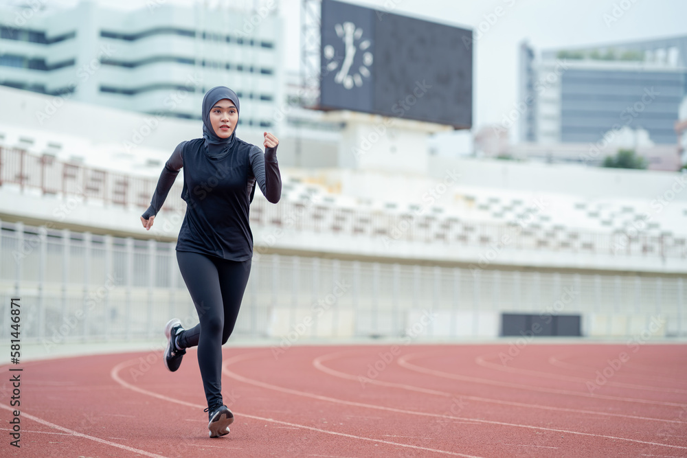A young asian Muslim woman wearing a black hijab is exercising and ...
