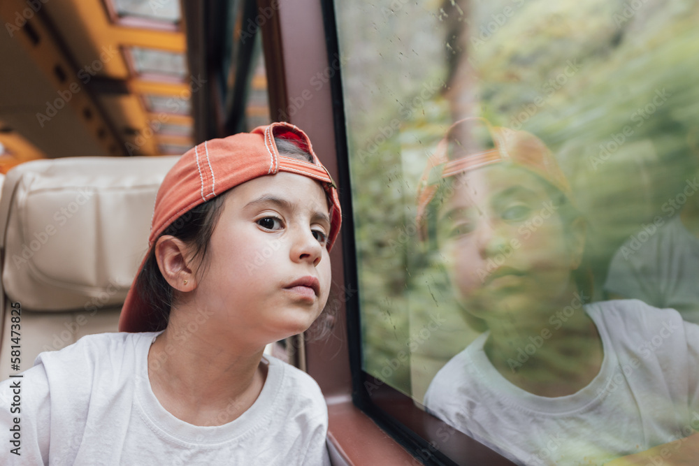 Little girl with cap travel on a train in Peru, looking through window ...