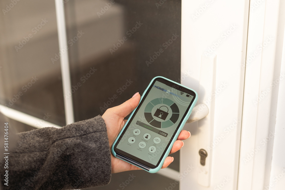 Foto de Woman locking smartlock on the entrance door using a smart ...