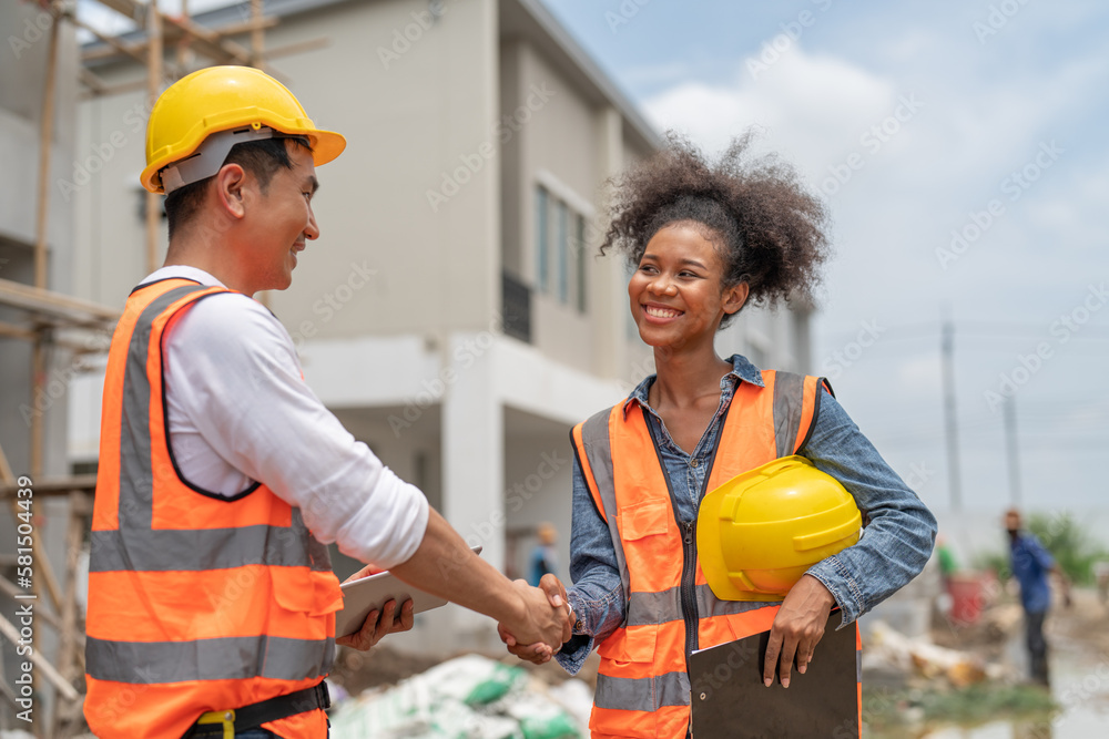 Happy female and male civil engineers in safety vest shaking hands to ...