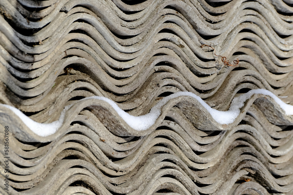 Pile of asbestos roof tiles with snow in the winter. Wavy industrial ...