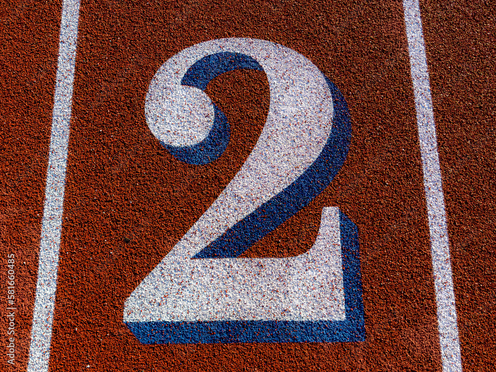 Close up lane number 2 on a new red running track with white lane lines ...