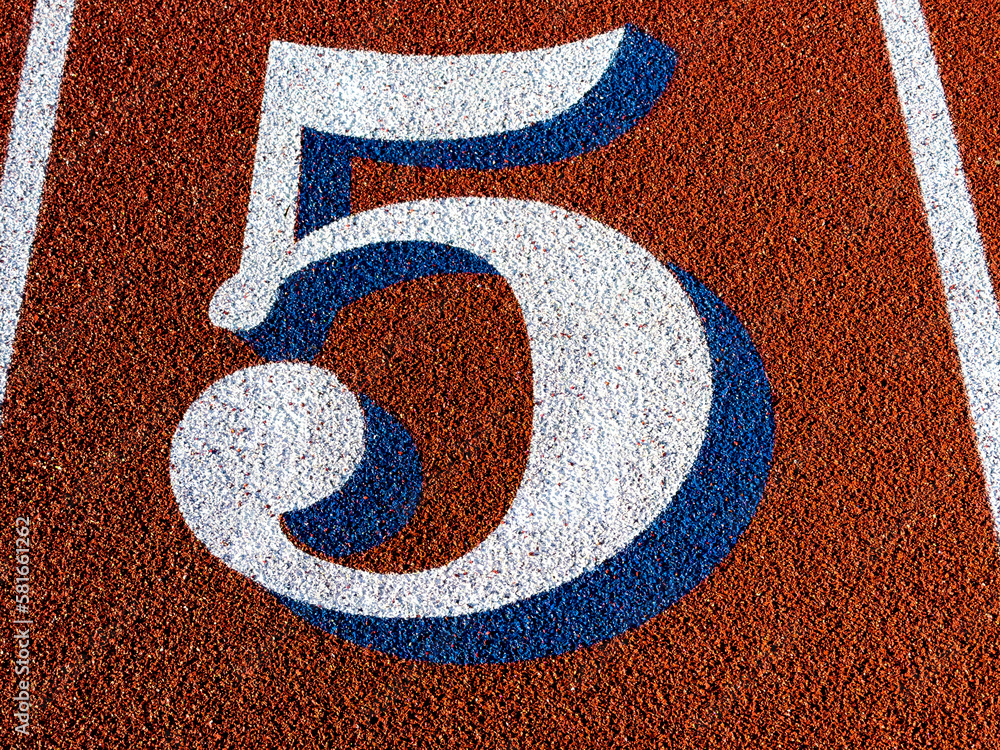 Close up lane number 5 on a new red running track with white lane lines ...