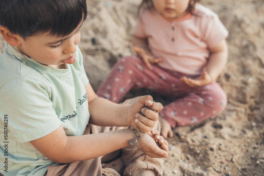 Two muddy child playing in the wet dirt sand having fun as they diging ...