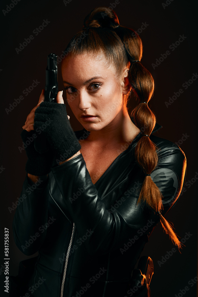 Portrait, gun and spy with a woman assassin in studio on a dark ...