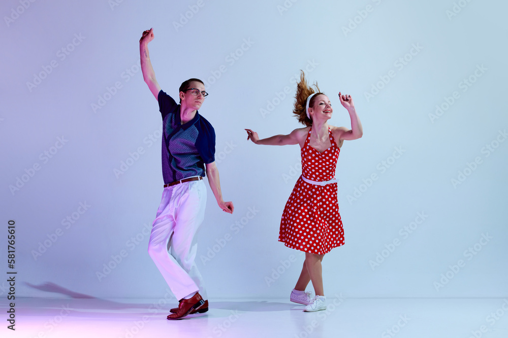 Young positive couple, man and woman in colorful costumes dancing retro ...