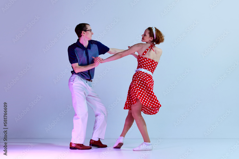 Beautiful young couple, man and woman in stylish costumes dancing retro ...