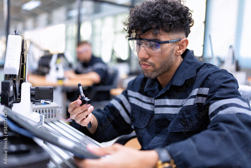 Engineer sitting in robot fabrication room quality checking robot arm ...