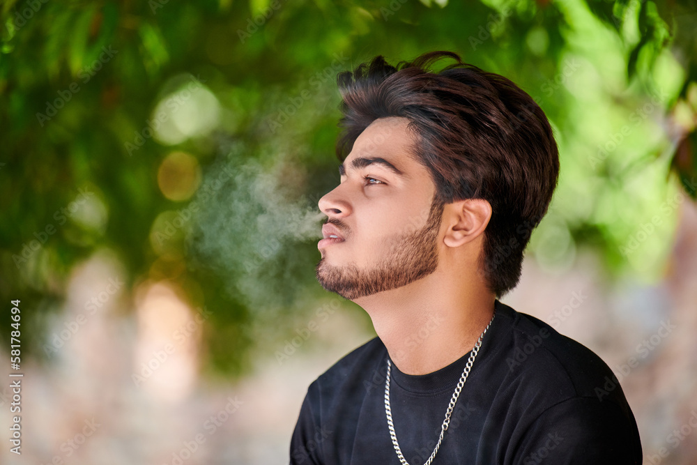 Attractive indian man smoker exhales cigarette smoke portrait in black ...